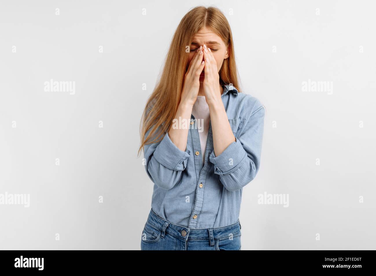 Portrait of depressed young woman covering face with hands, on isolated ...