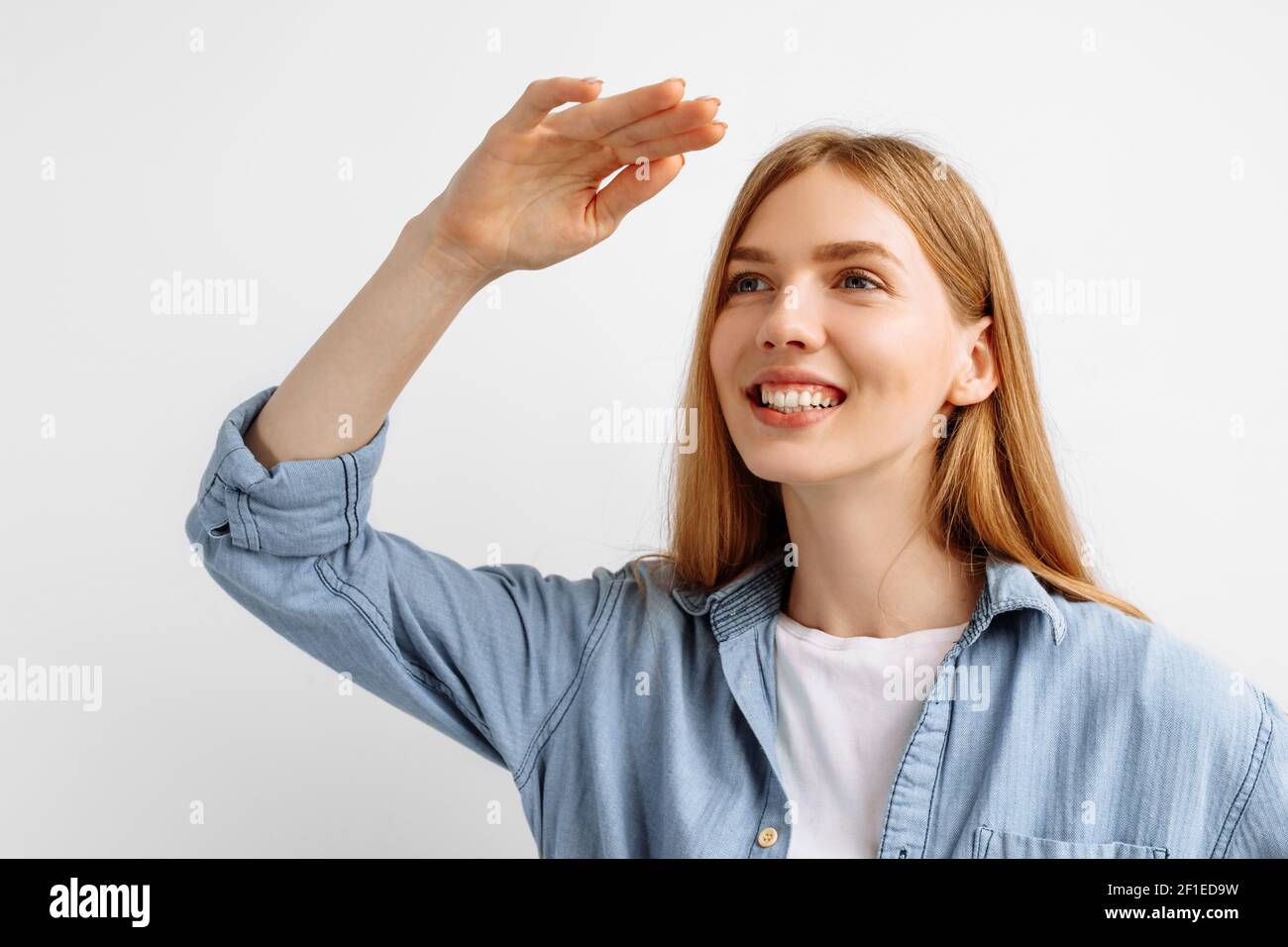 Happy young woman stands and looks into the distance with hand on ...