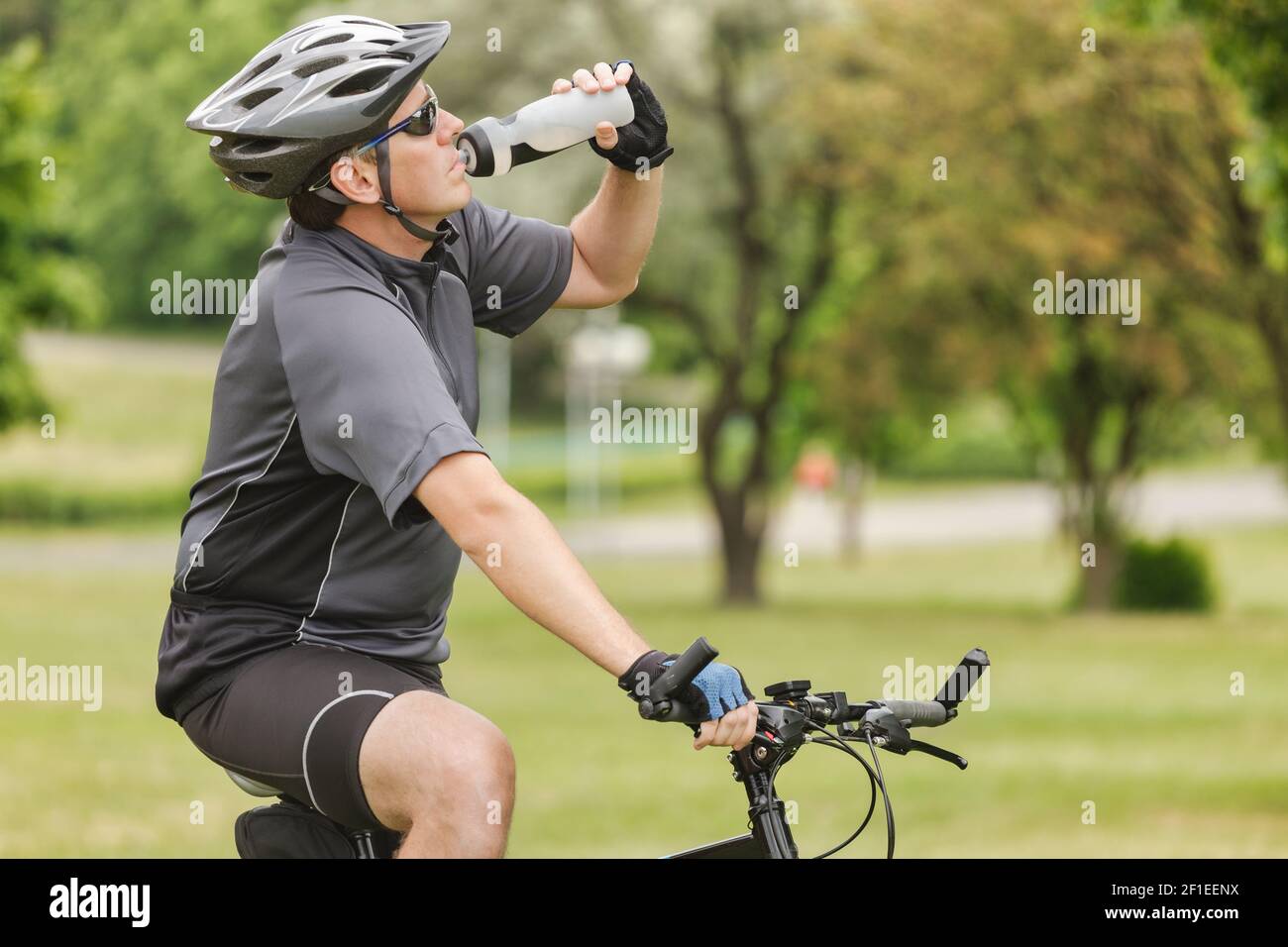 Cyclist drinks water from a bottle while riding a bike Stock Photo - Alamy
