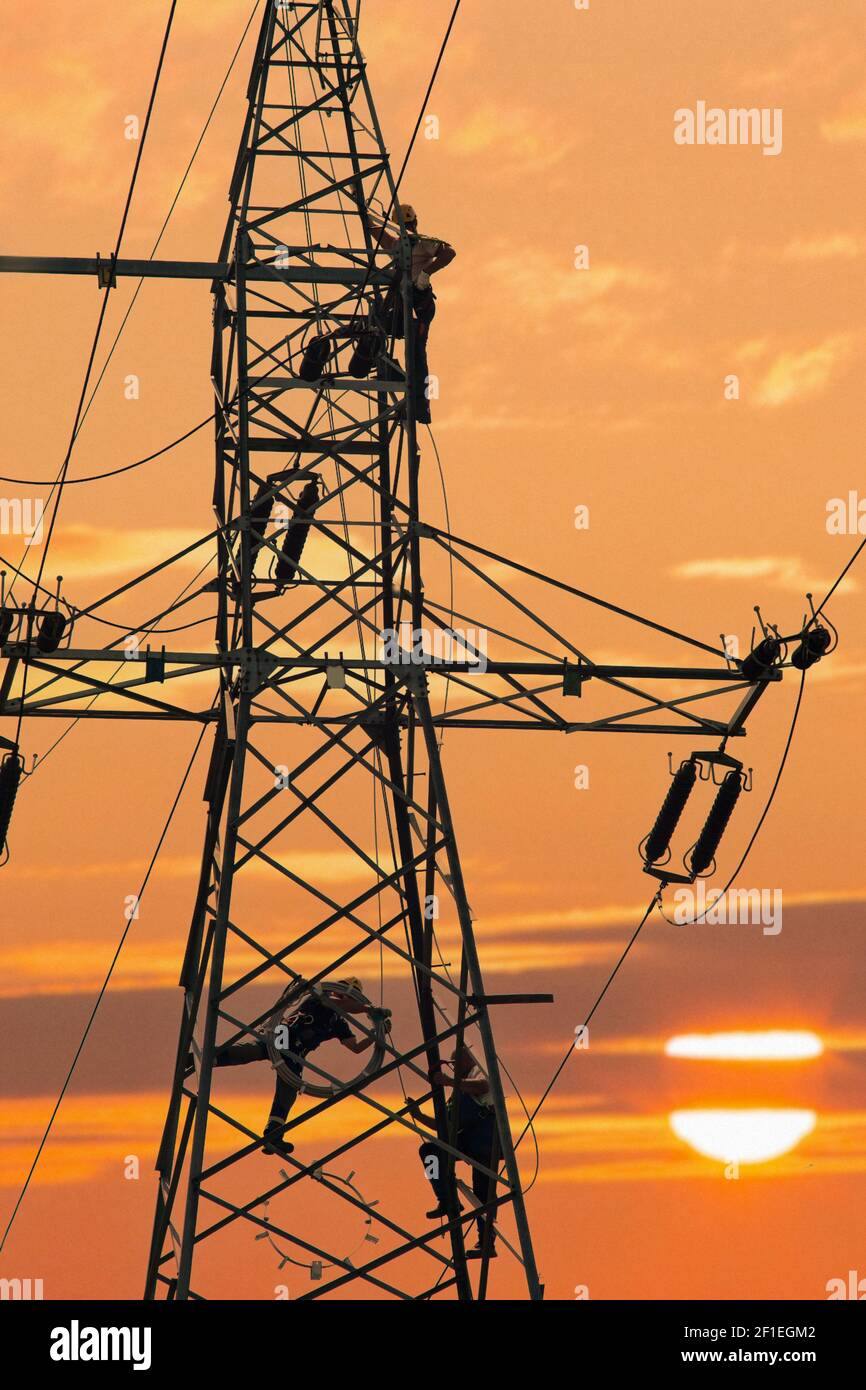 Shadow electricians repairing wire on electric power pole at the ...