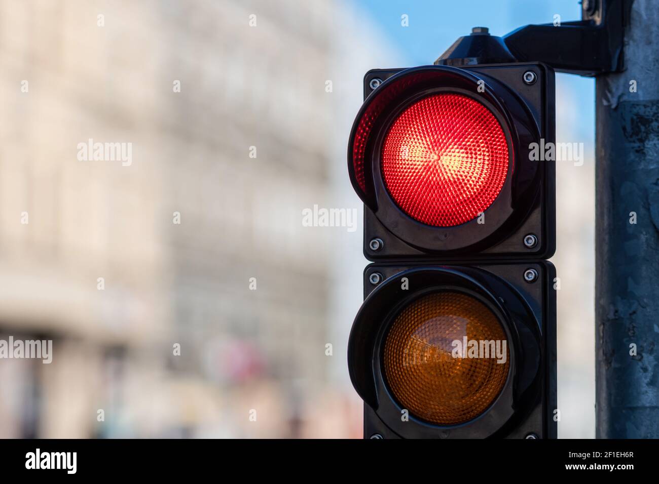 closeup of traffic semaphore with red light on defocused city street ...