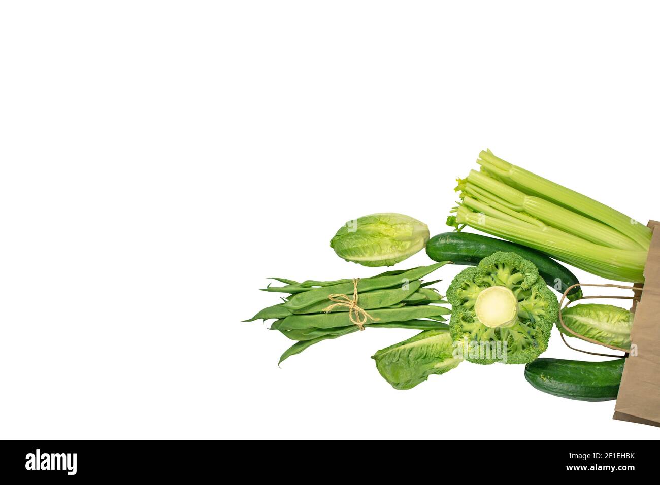 Green colored vegetables flying from the kraft paper bag isolated on ...