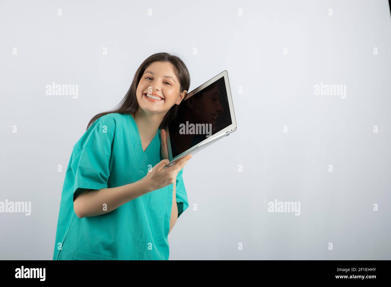 Happy female nurse posing with laptop on white background Stock Photo ...