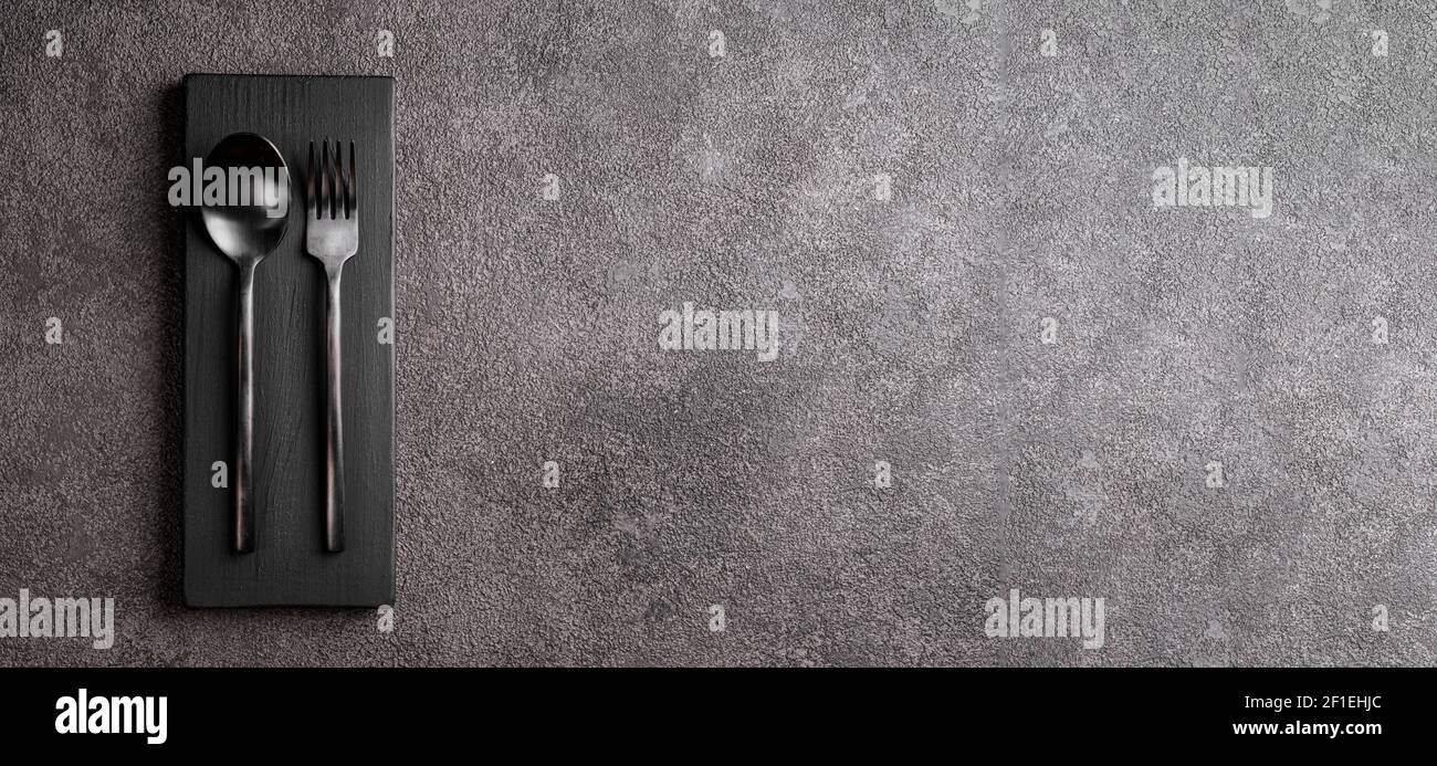 black matte fork and spoon. gray background of the copy space concept ...