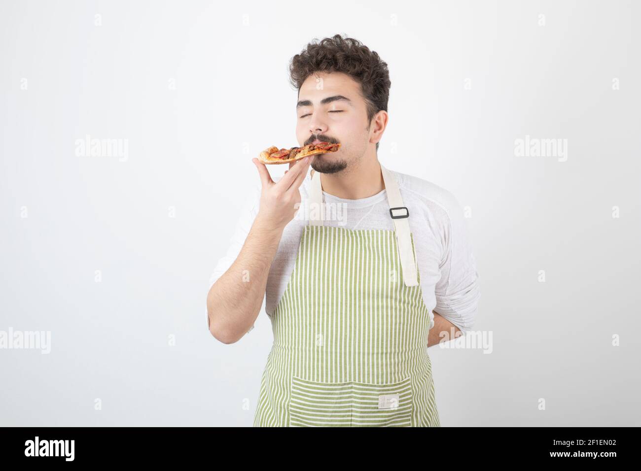 Image of male cook eating slice of pizza on white background Stock ...