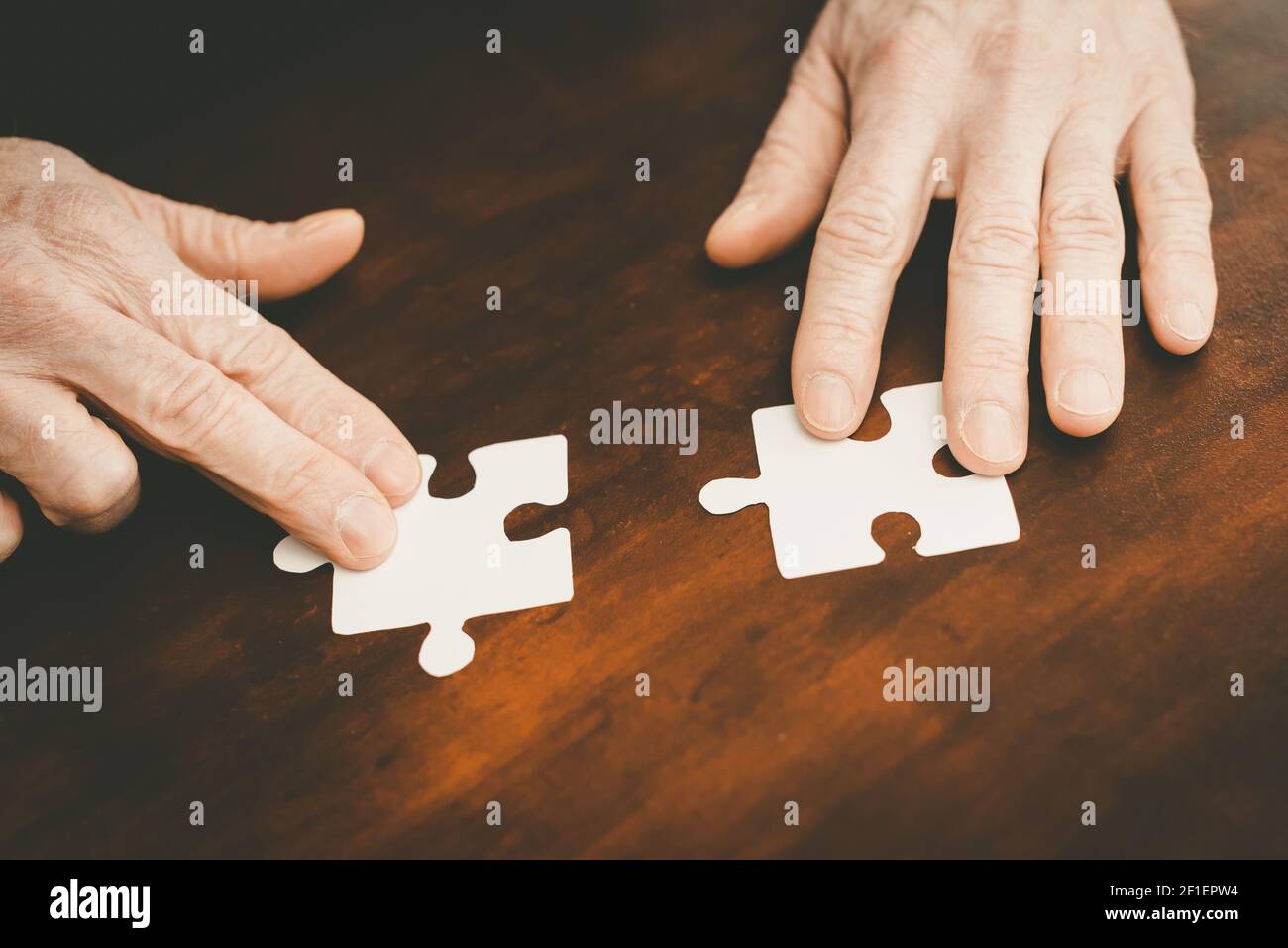 Hands joining two puzzle pieces, teamwork concept Stock Photo - Alamy