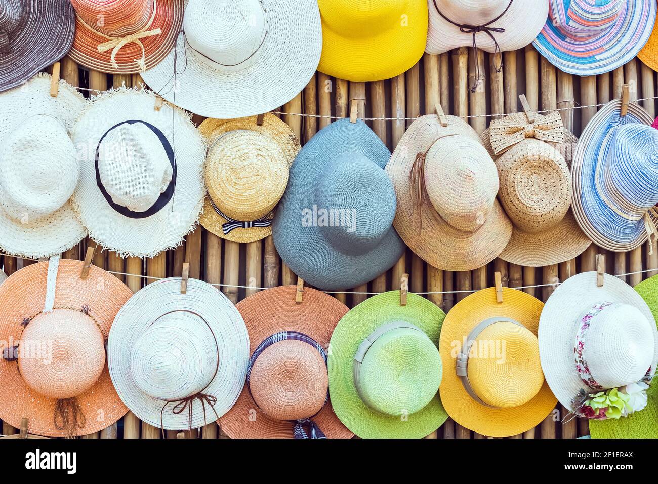 A variety of fashionable and colorful hats hanging on the bamboo ...