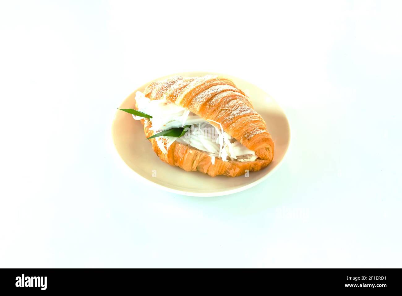 Freshly baked croissant stuffed with fresh coconut on white plate ...
