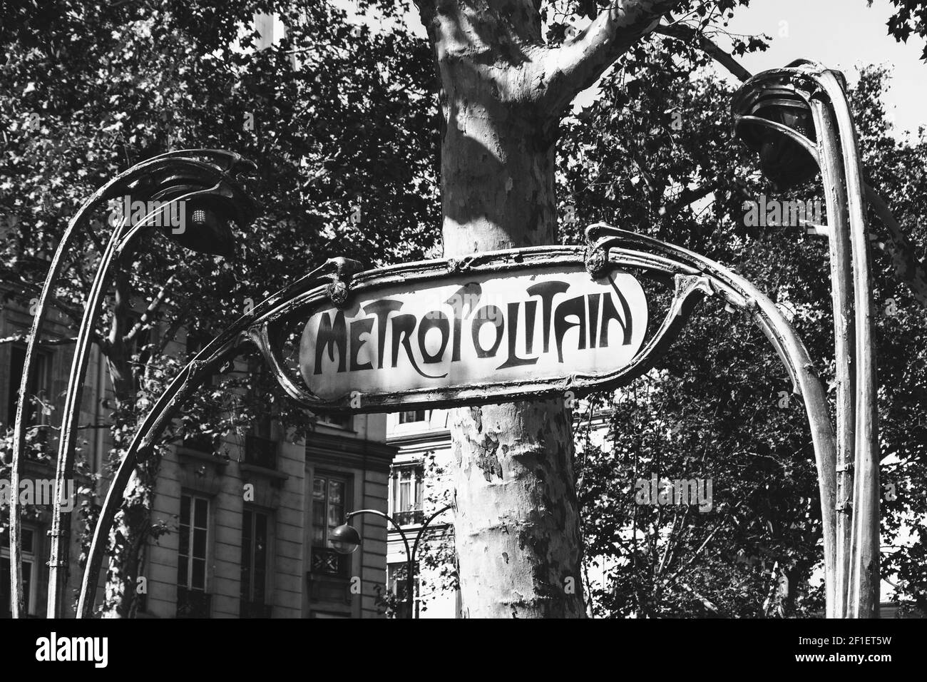 Parisian metro sign on empty street in sunny day. Plane trees and ...