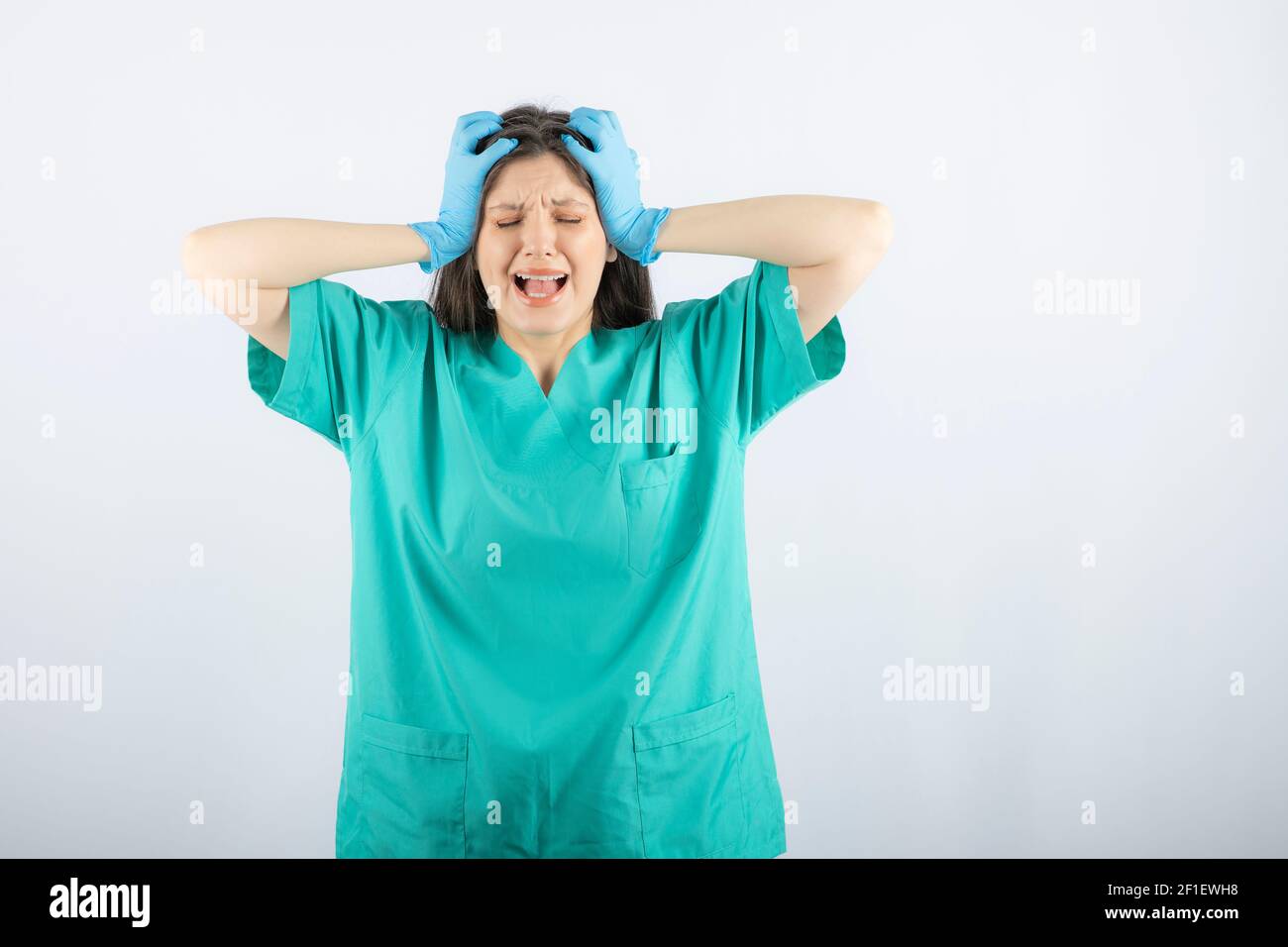 Female doctor wearing green medical uniform and holding head Stock ...