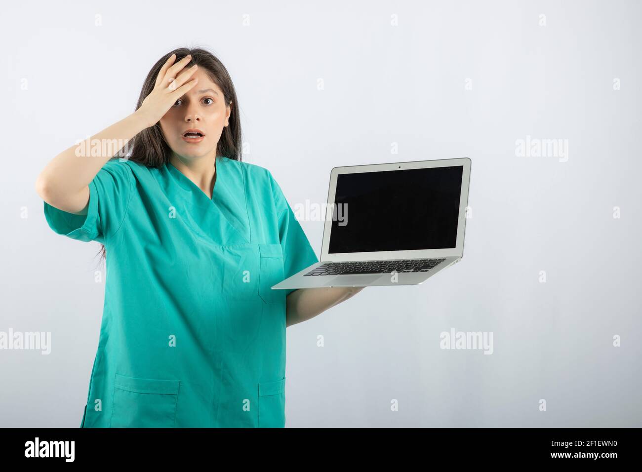 Young female nurse posing with laptop and getting scared Stock Photo ...