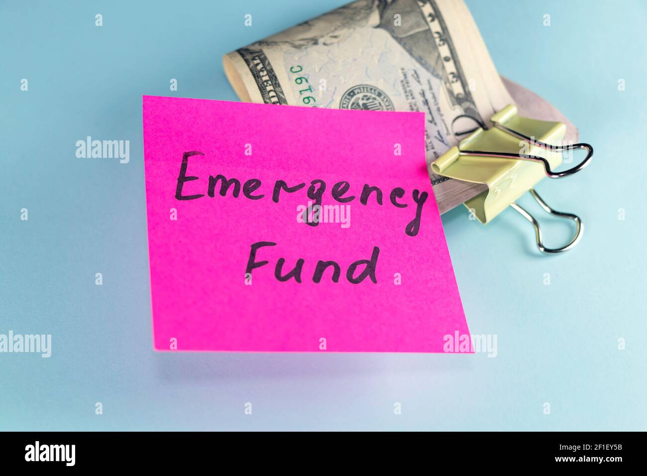 US dollars in paper clip on pastel blue background with note written ...