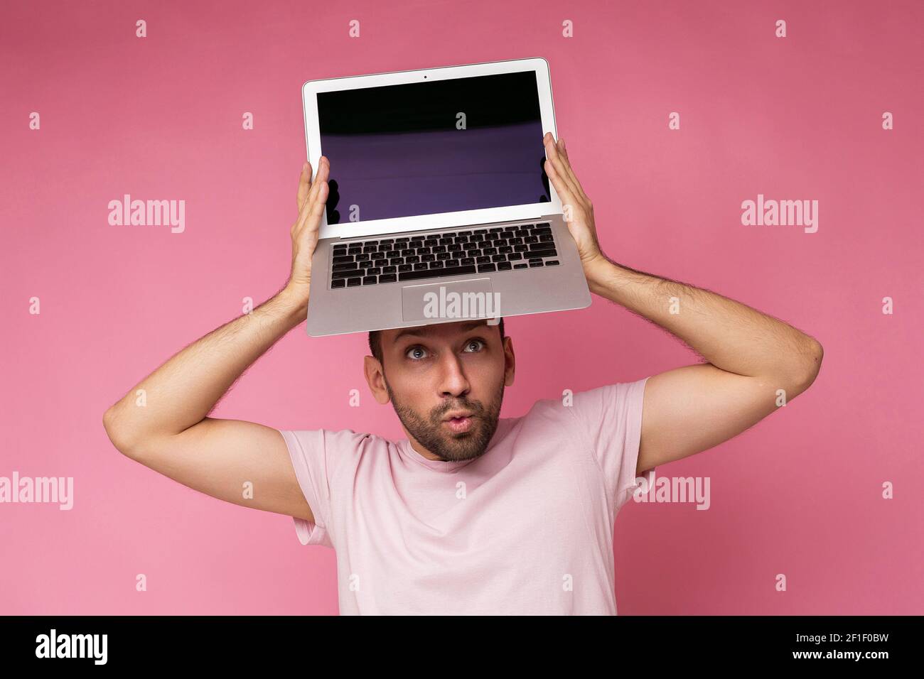 Handsome surprised and amazed man holding laptop computer looking up in ...