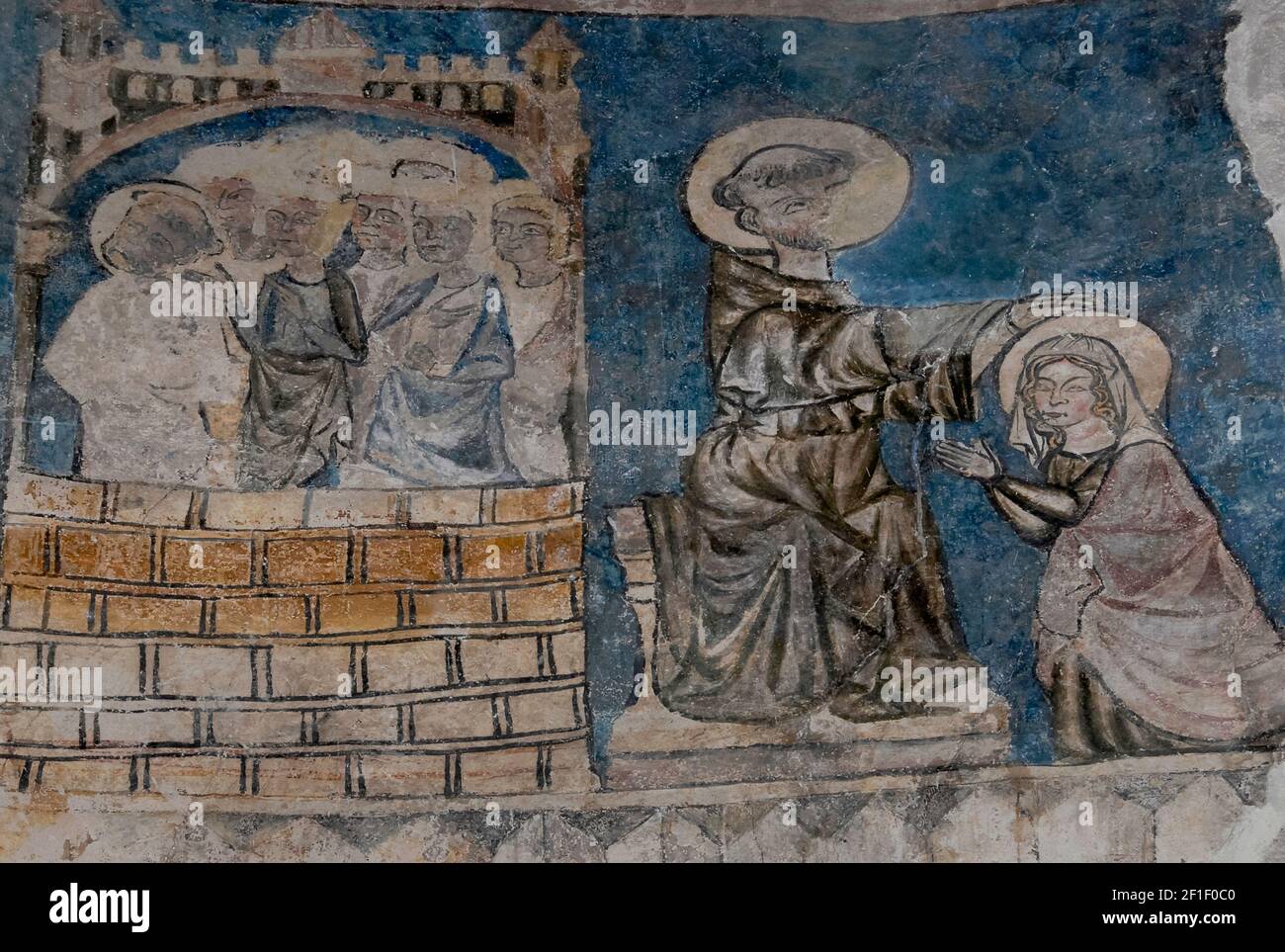 A tonsured monk looks up to heaven as he blesses a praying woman ...