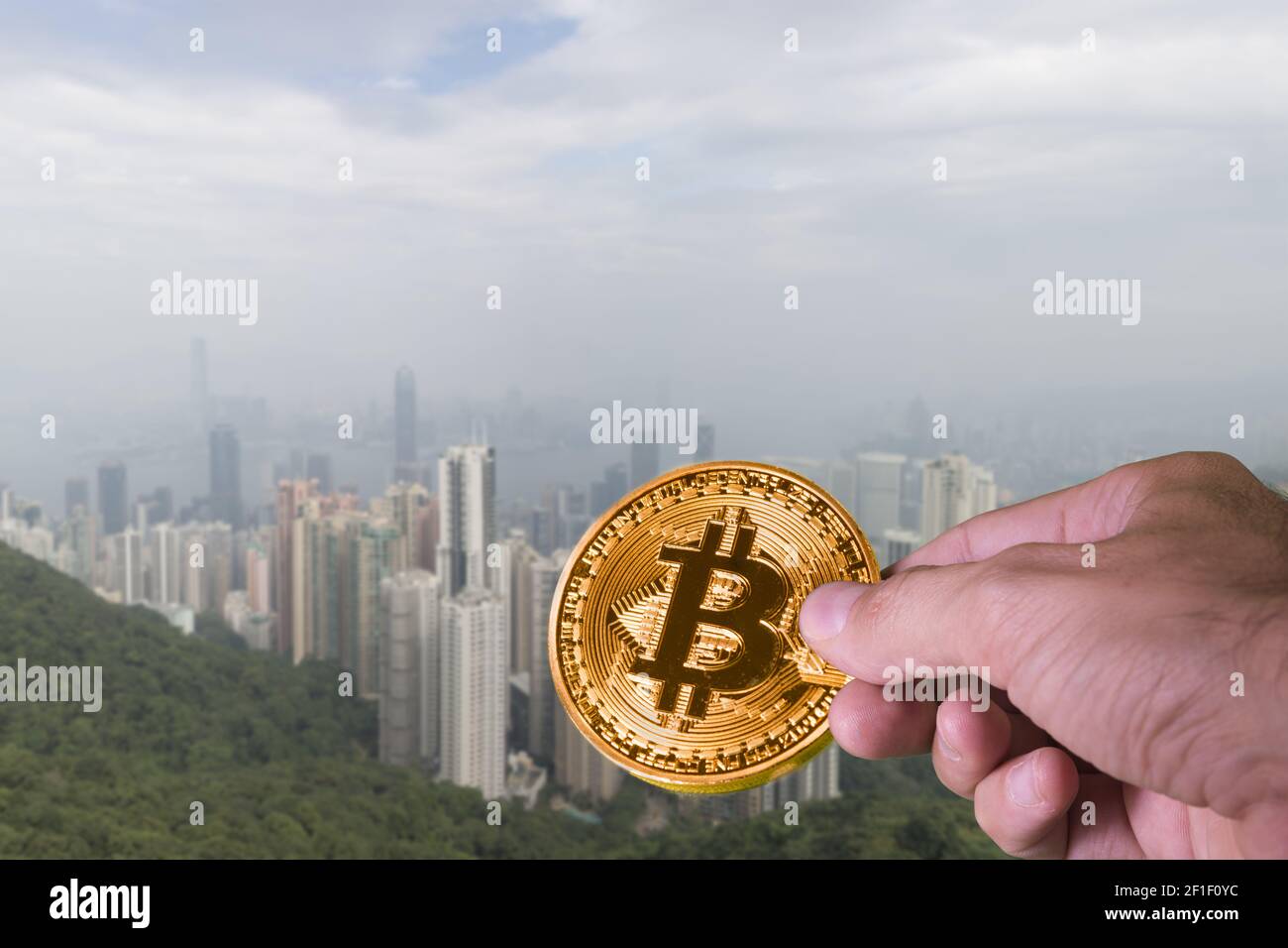 Hand holding a bitcoin and Hong Kong in the background Stock Photo - Alamy