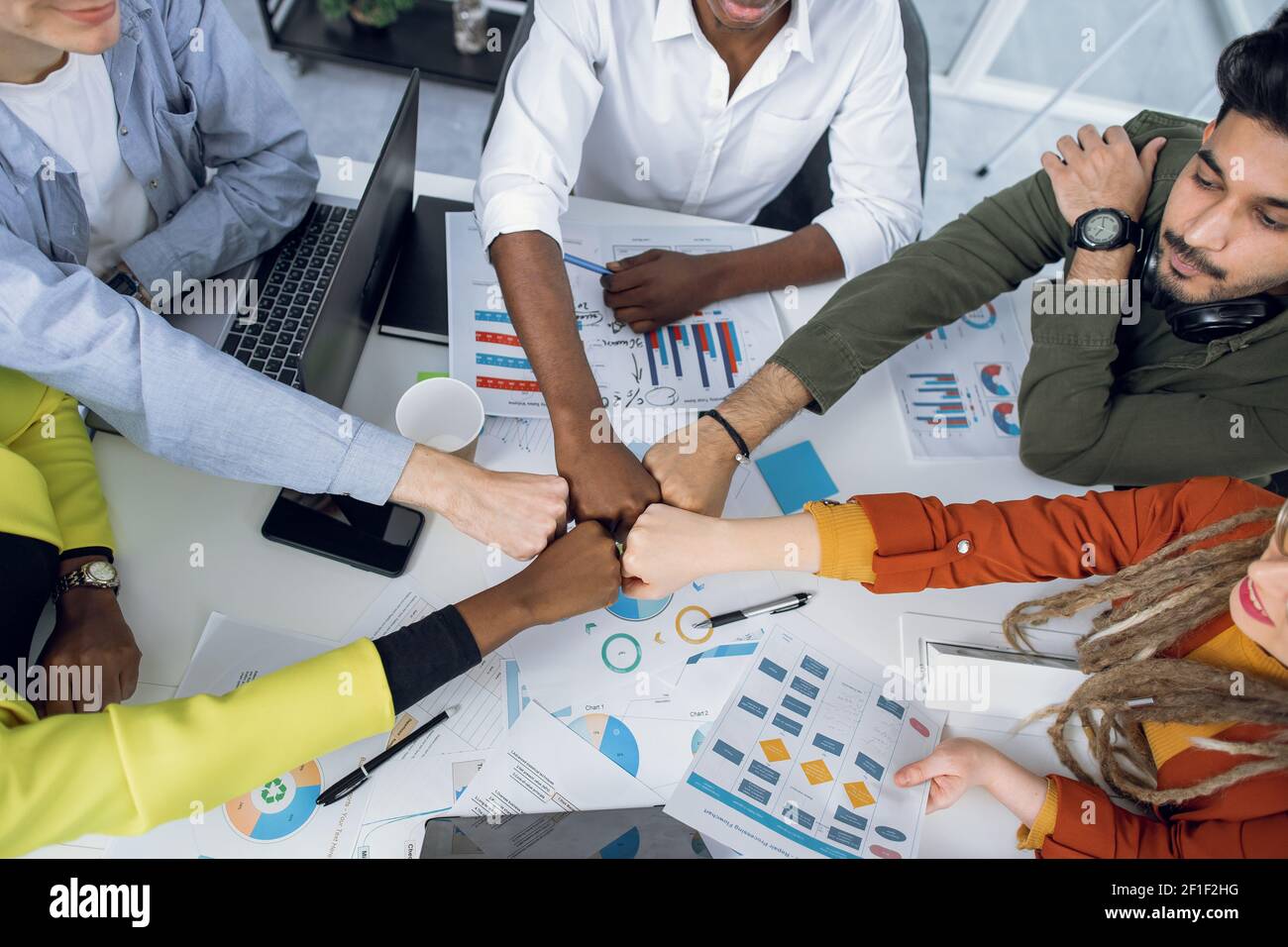 Five multi ethnic students bumping with fists at office Stock Photo - Alamy