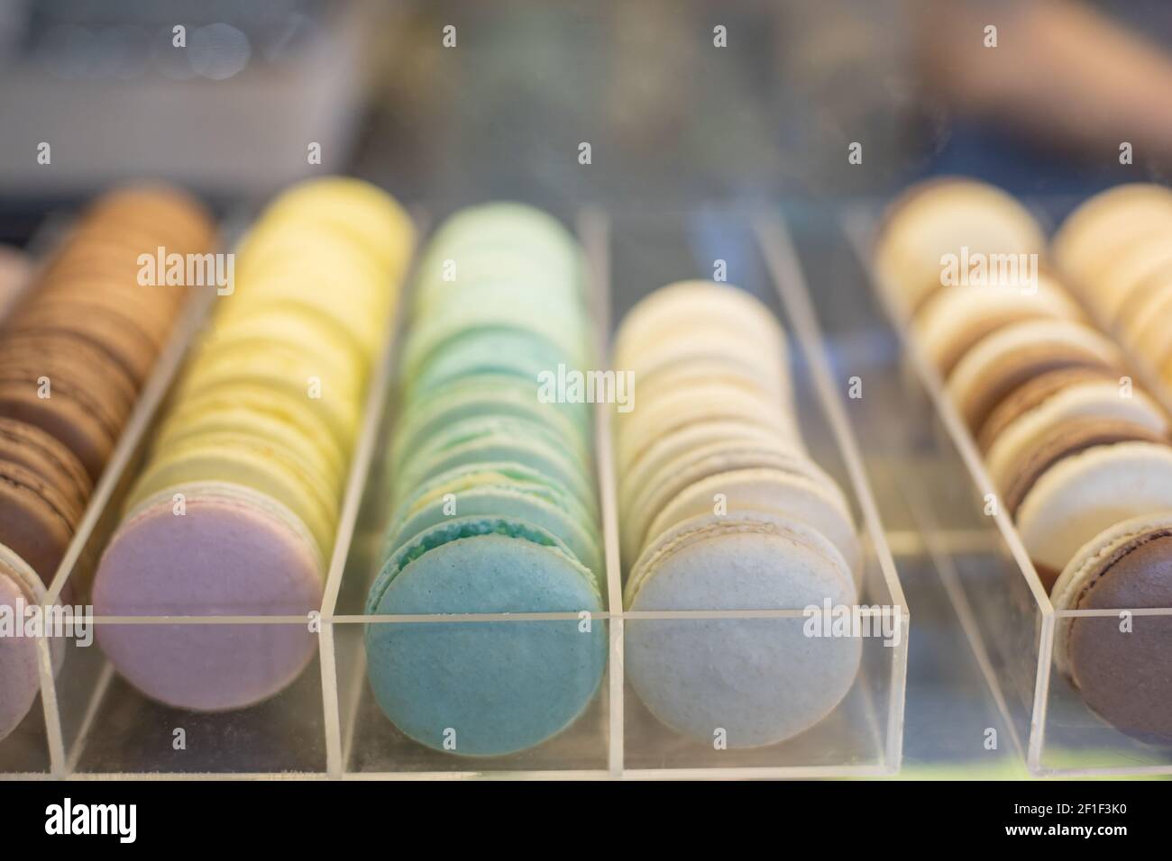 Many colorful macaron eclair in glass showcase at candy shop close up ...