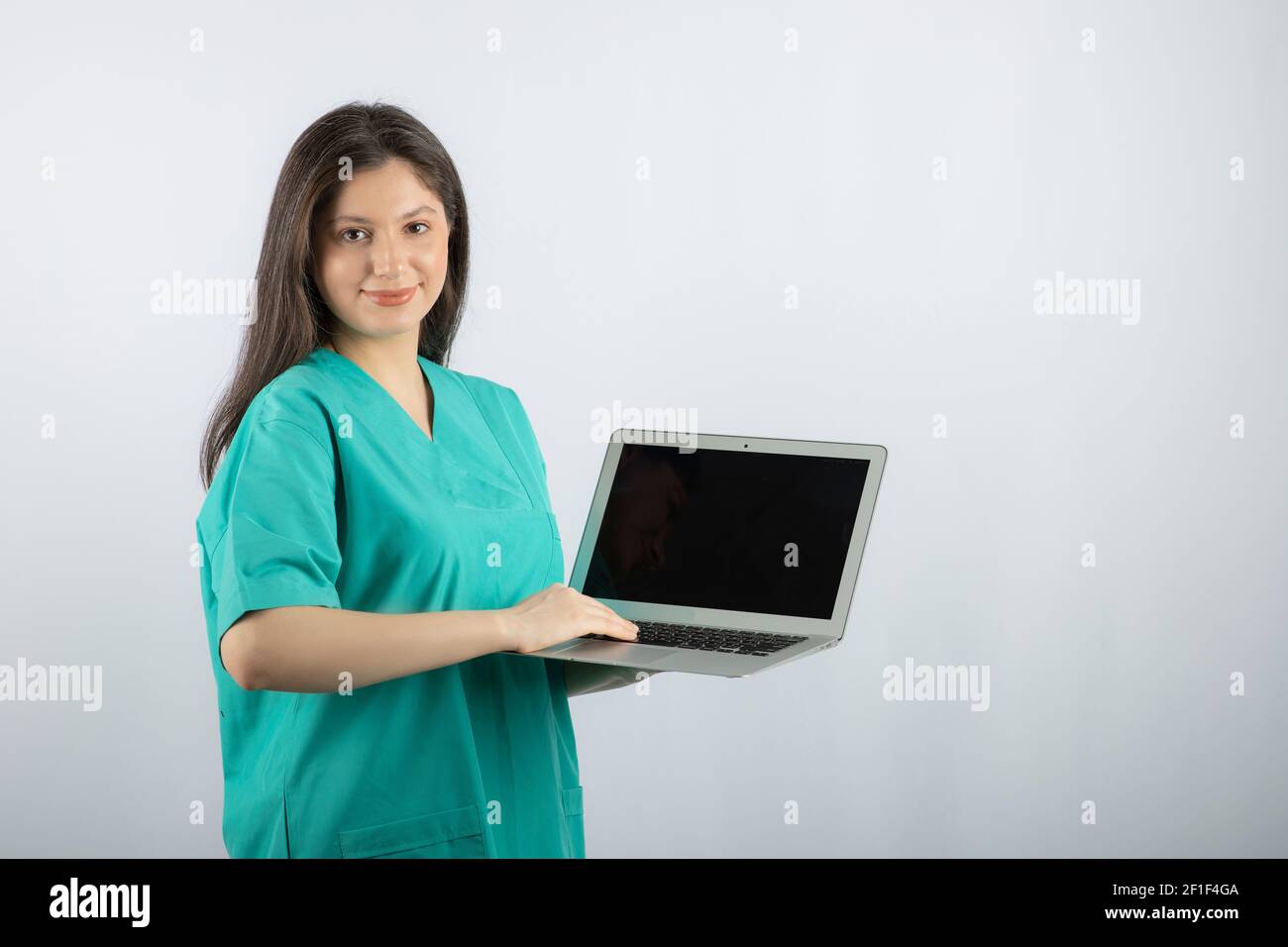 Young female nurse with laptop standing on white background Stock Photo ...