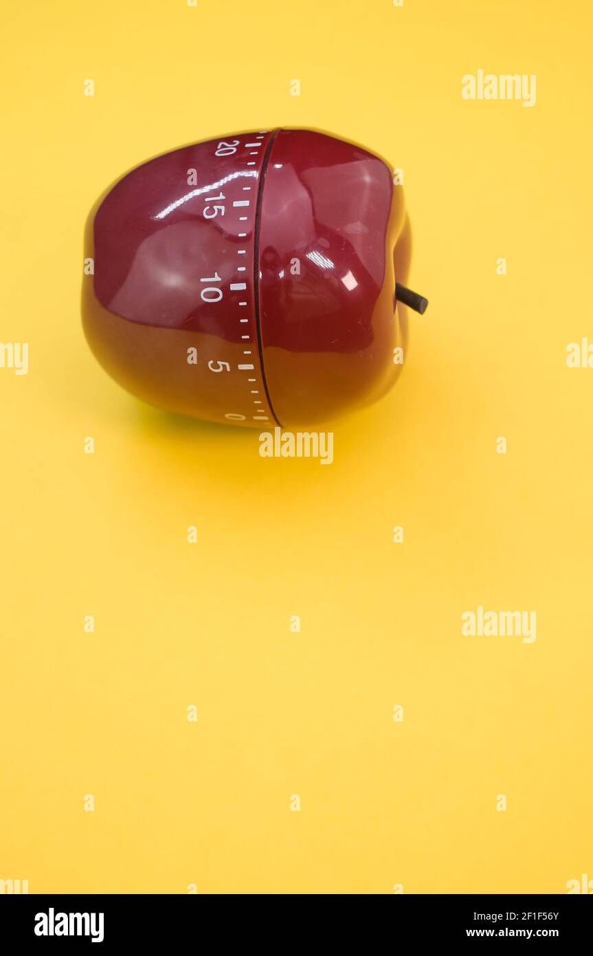 A vertical shot of an apple-shaped kitchen timer isolated on yellow ...