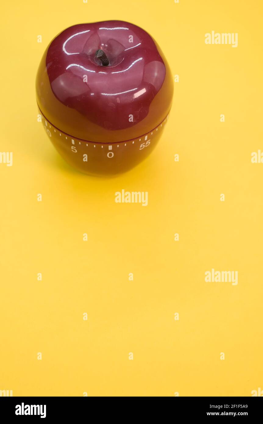 A vertical shot of an apple-shaped kitchen timer isolated on yellow ...