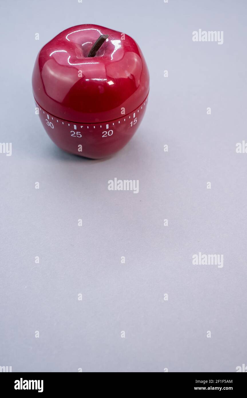 A vertical shot of apple-shaped kitchen timer isolated on light blue ...