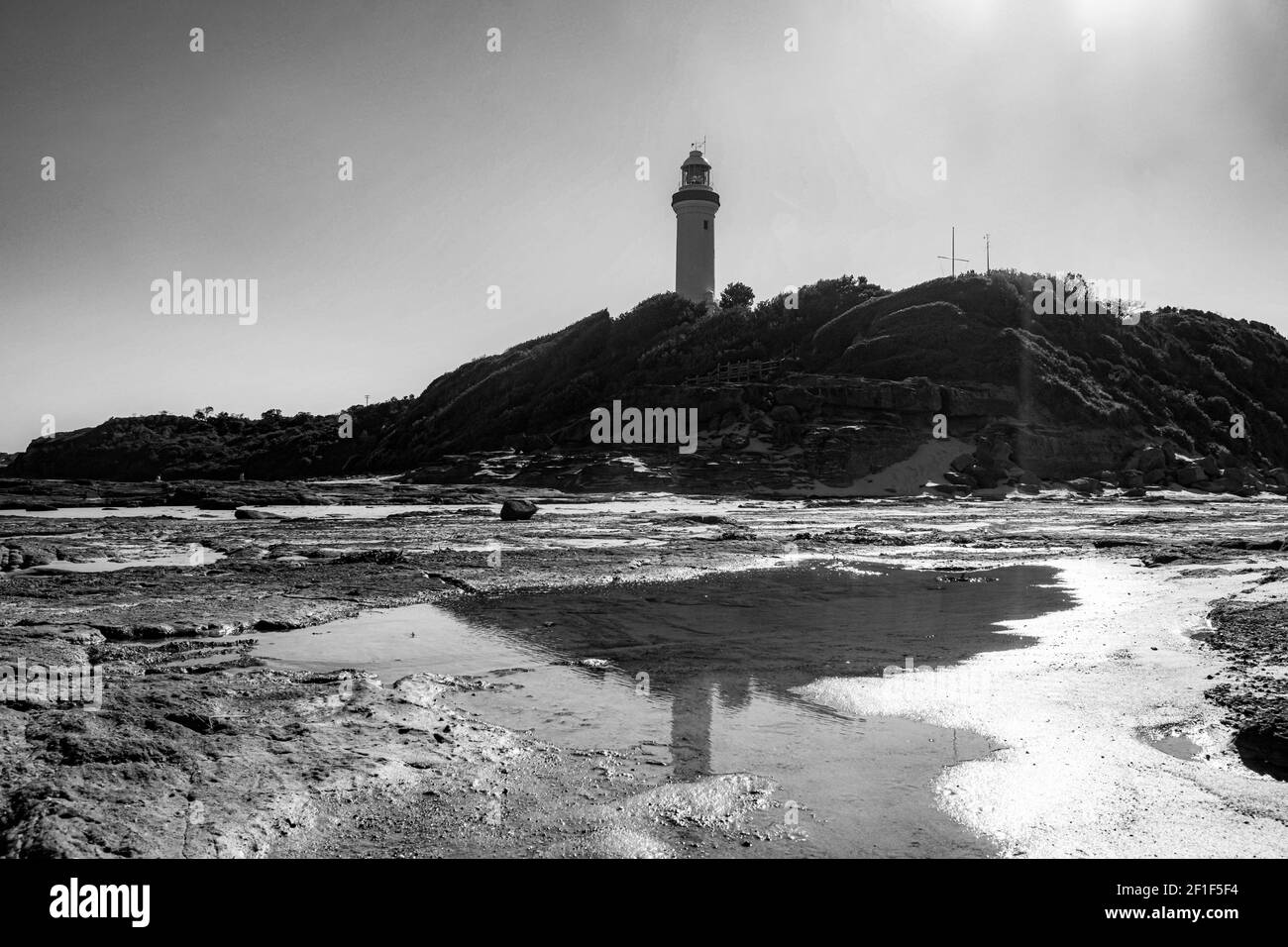 A grayscale of a lighthouse on the rocky seashore Stock Photo - Alamy