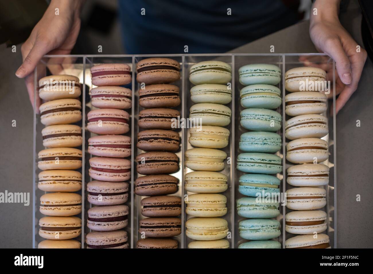 Many colorful macaron eclair in glass showcase at candy shop close up ...