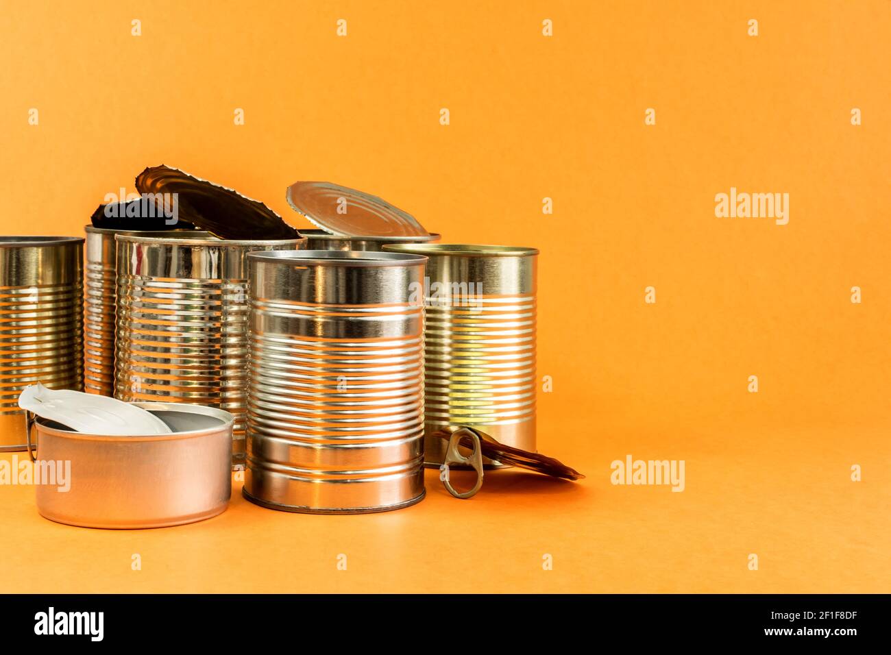 A closeup of empty metal tins and cans isolated on an empty orange ...