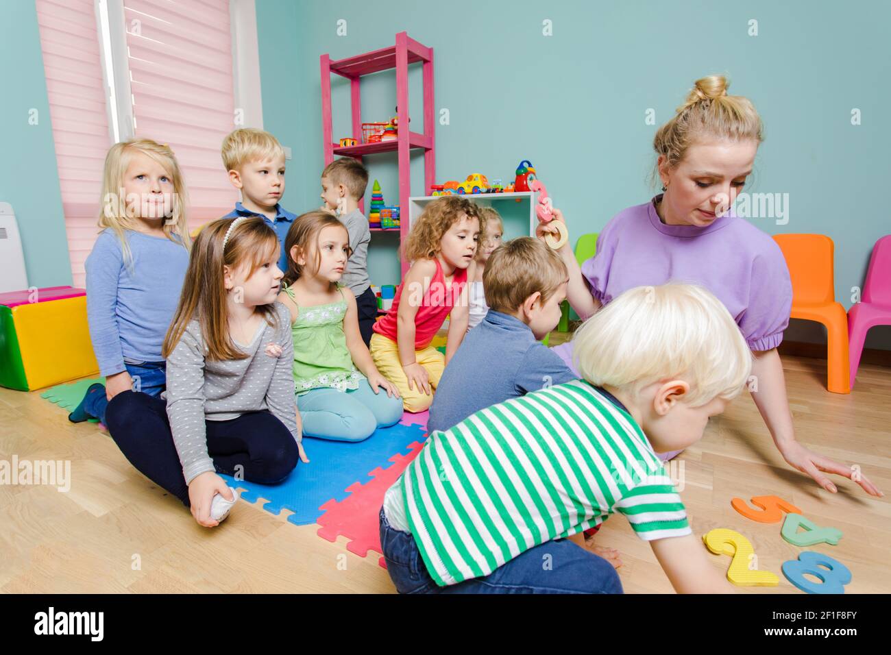 Lovely preschoolers listening young teacher very carefully Stock Photo ...