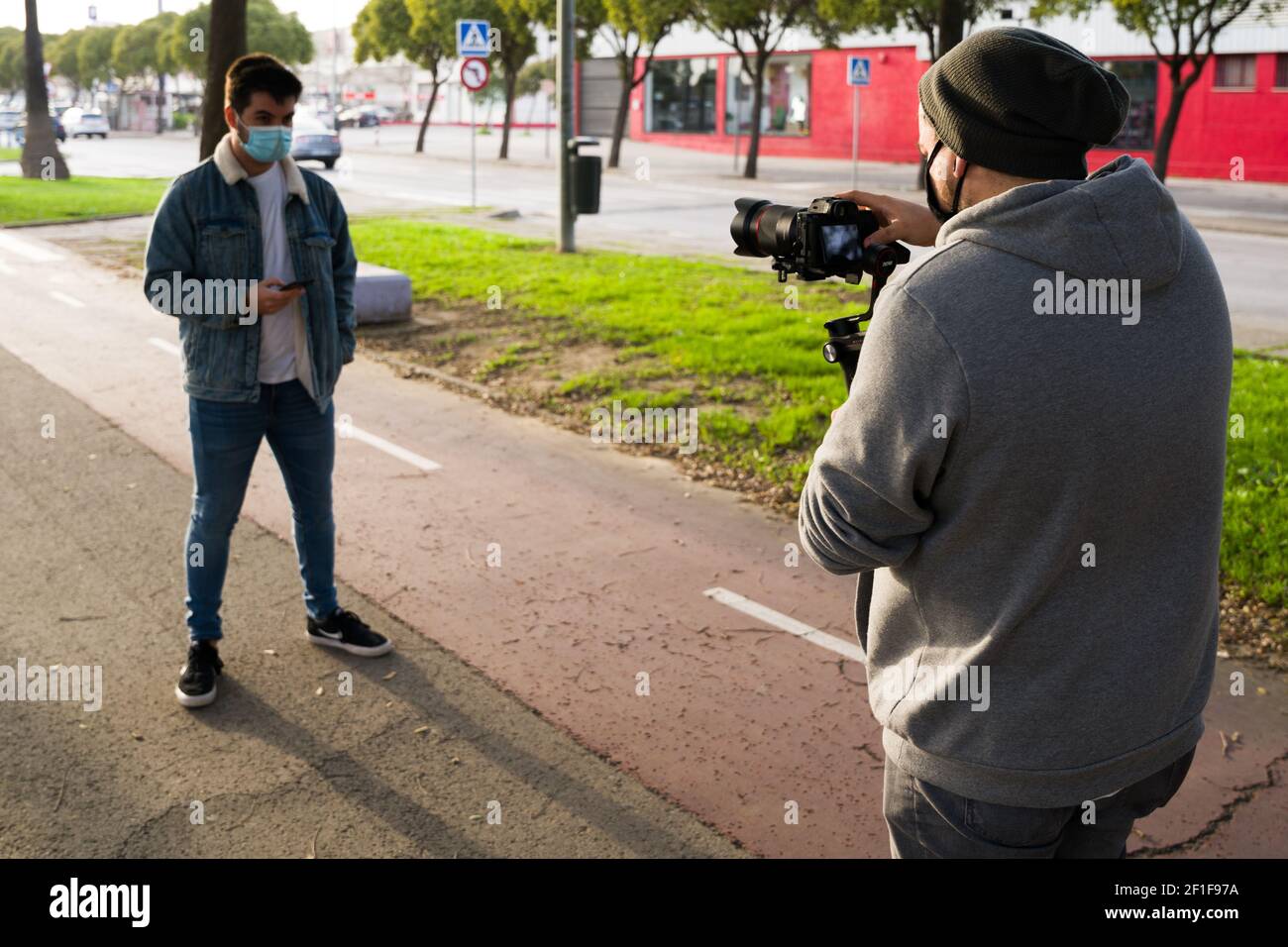 A side view of a cameraman shooting a young handsome guy standing on a ...