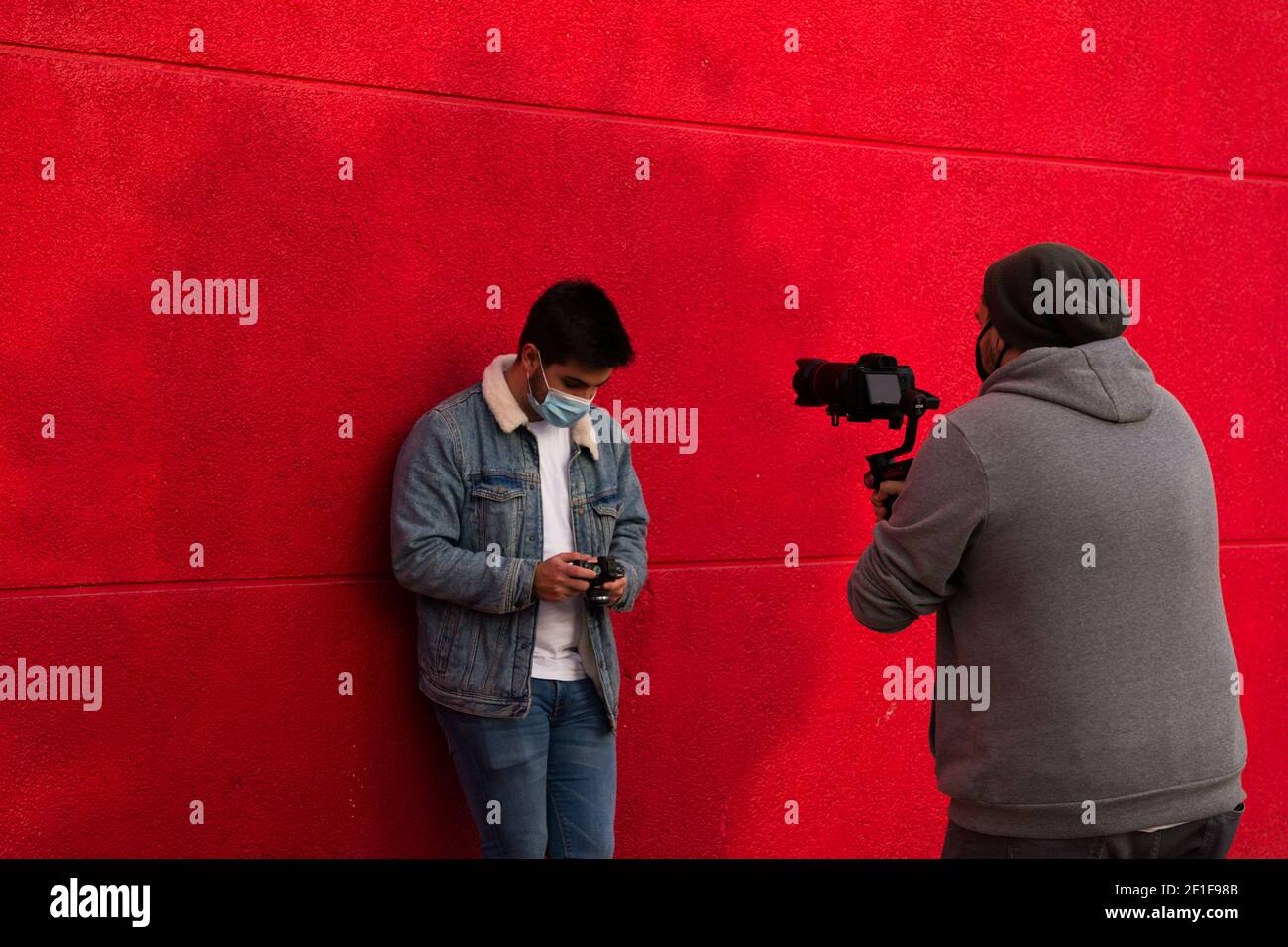 A side view of a cameraman shooting a young handsome guy looking at the ...