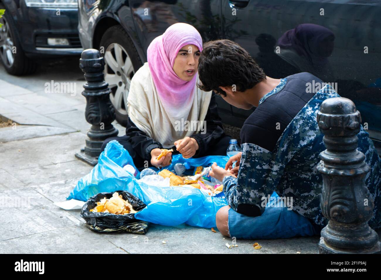 Poor muslim woman in hijab and man sit on sidewalk and eat leftovers ...
