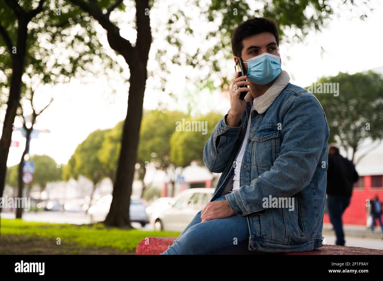 A side view of a young handsome man with a medical face mask talking on ...