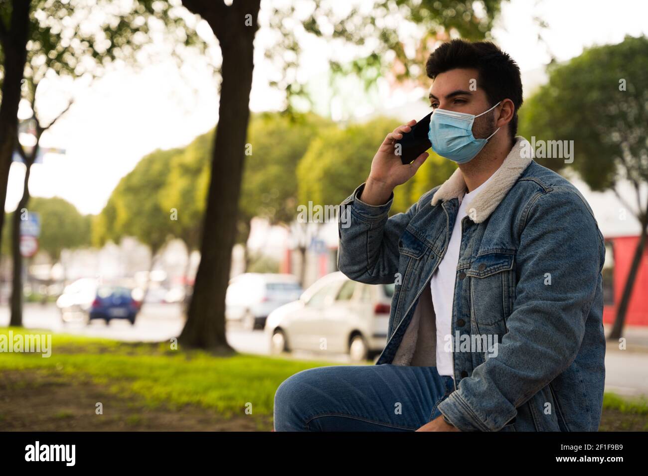 A side view of a young handsome man with a medical face mask talking on ...