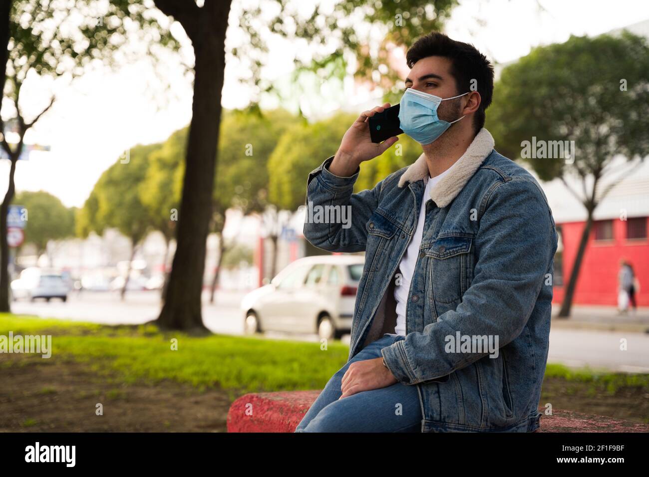 A side view of a young handsome man with a medical face mask talking on ...