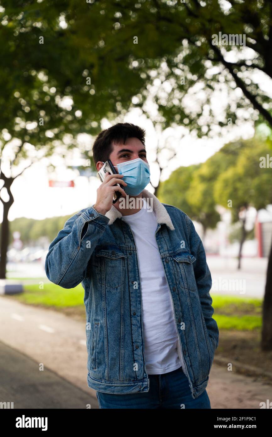 A side view of a young smiling handsome man with a medical face mask ...