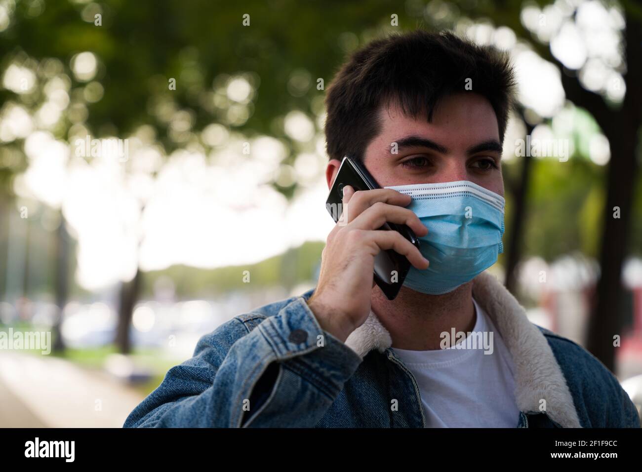 A closeup shot of a young handsome man with a medical face mask talking ...