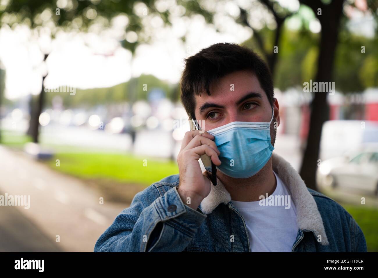 A closeup shot of a young handsome man with a medical face mask talking ...