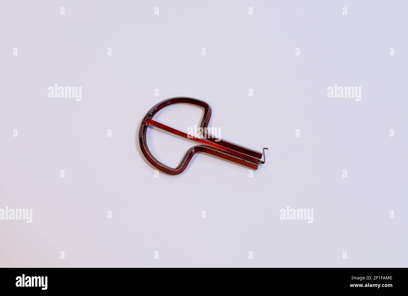 A top view closeup of a tiny metallic jew's harp on a white background ...
