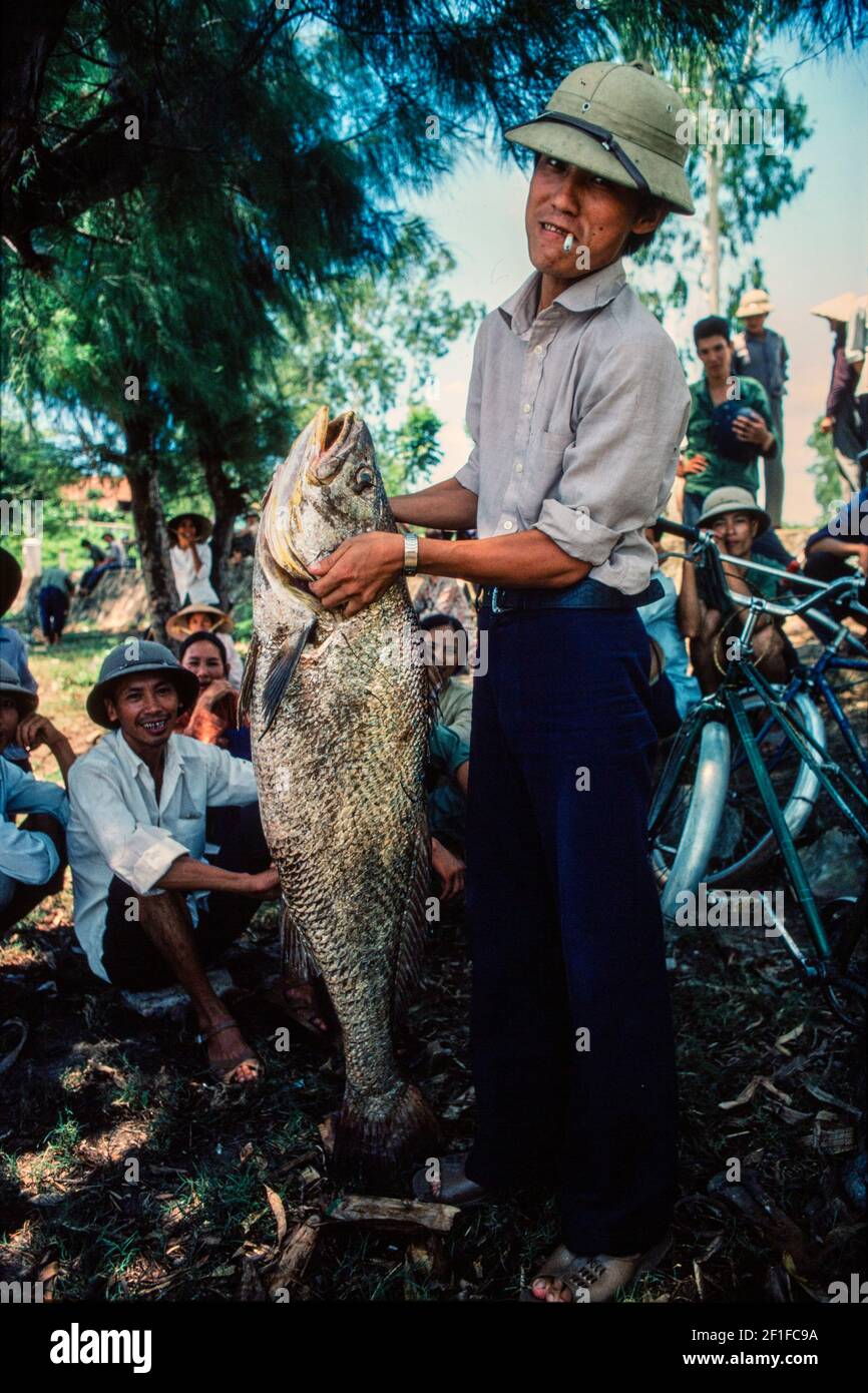 A fisherman with a large fish he has caught, coastal village, North ...
