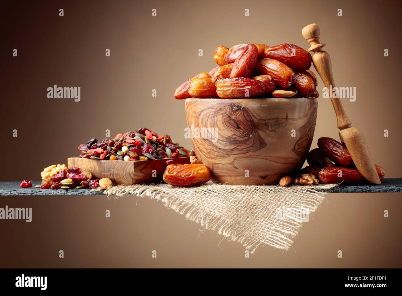 Dates and dried fruits, nuts and seeds on a brown background. Copy ...