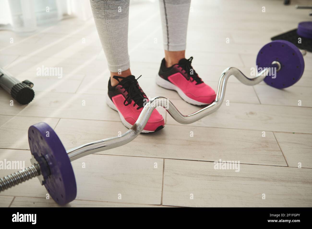 Close up of training pink sneakers and barbell on floor at home gym ...