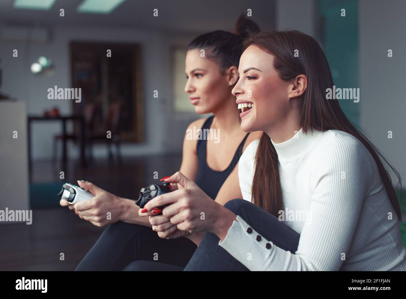 Happy young Caucasian friends playing on console at home, laughing ...
