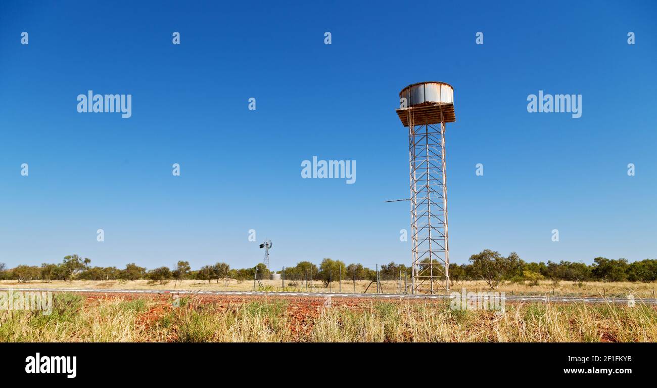 In the outback with asphalt line and water tank Stock Photo - Alamy