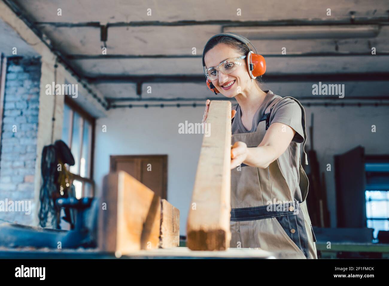 Beautiful woman carpenter checking quality of a plank Stock Photo - Alamy
