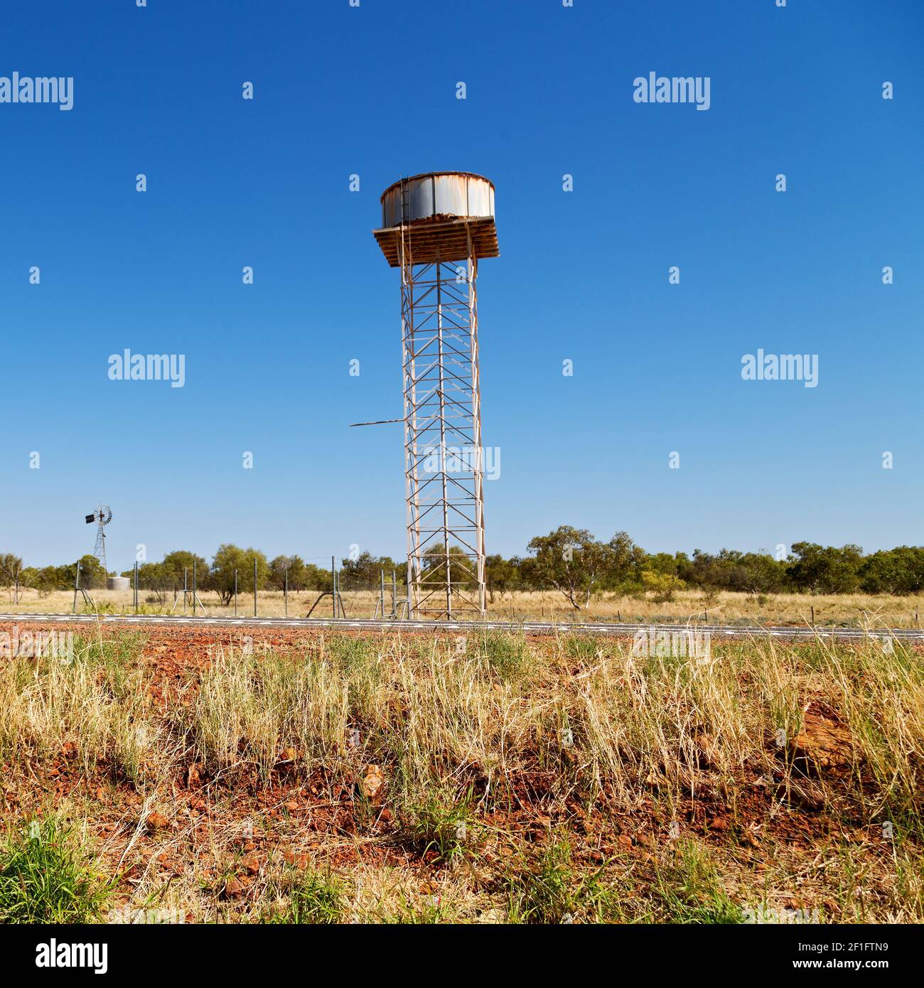 In the outback with asphalt line and water tank Stock Photo - Alamy