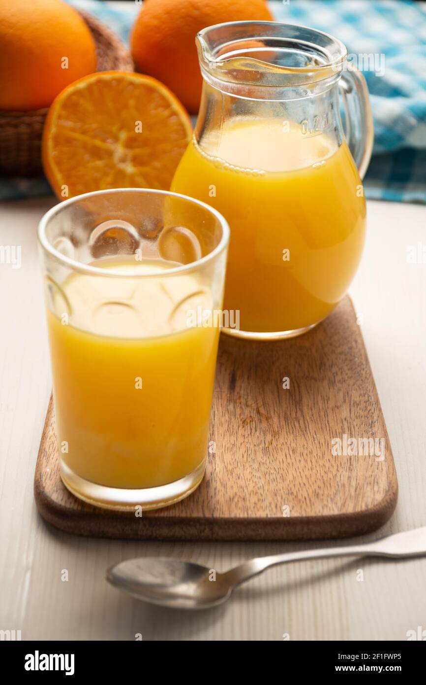 Top view of glass and jug with orange juice, spoon, half orange and ...