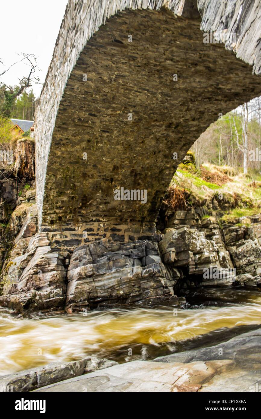 A single arched stone bridge crossing the fast flowing Feshie River in ...