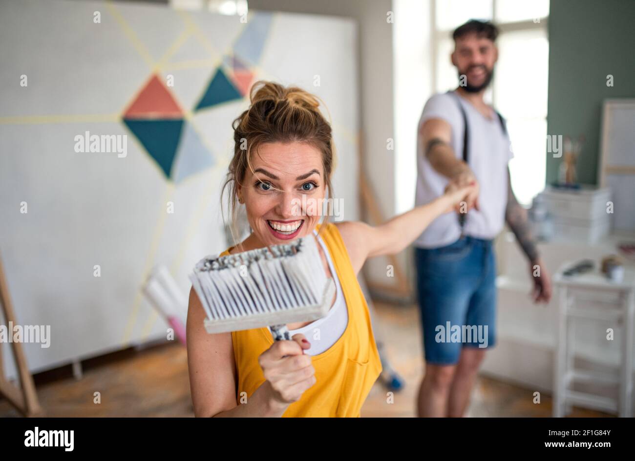 Couple having fun when painting wall indoors at home, relocation and ...