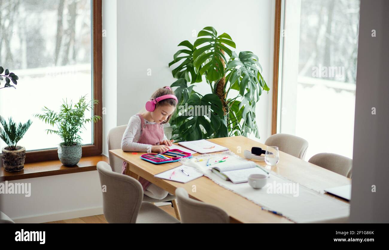 School girl sitting and working at table indoors at home, distance ...